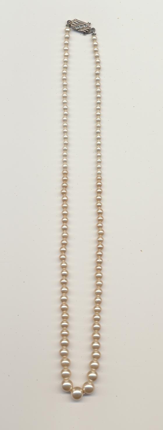 A missing bead in a necklace of faux pearls made of graduated pearl ...